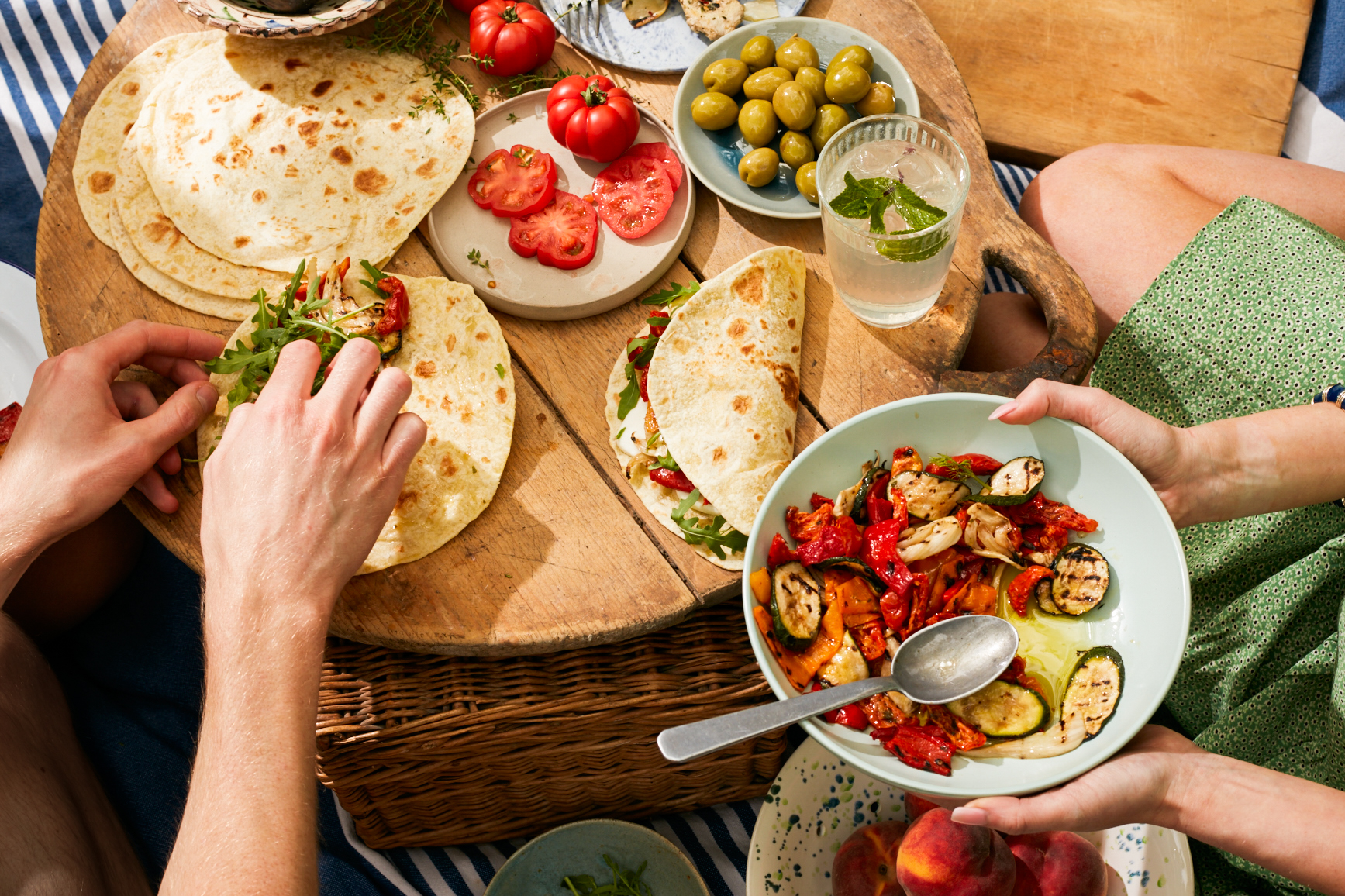 Piadian are being filled on a table, someone is holding a bowl of ...